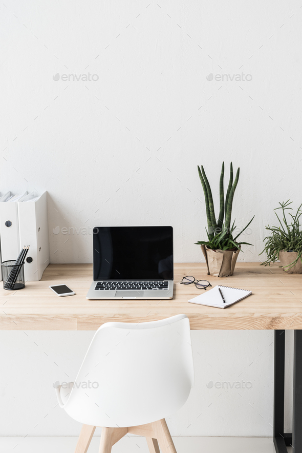 workplace with laptop computer and flower pots in modern office Stock ...