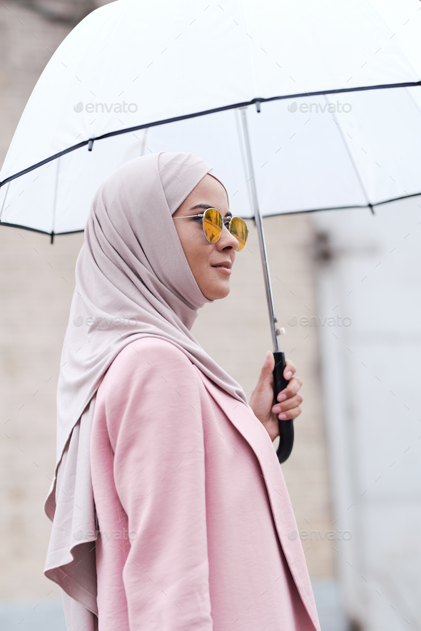 Young stylish Muslim woman in hijab, sunglasses and cardigan holding ...