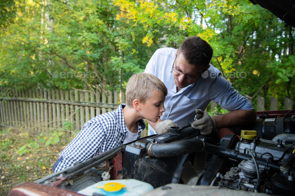 Dad and his son repairing car with open hood outdoors, fixing engine ...