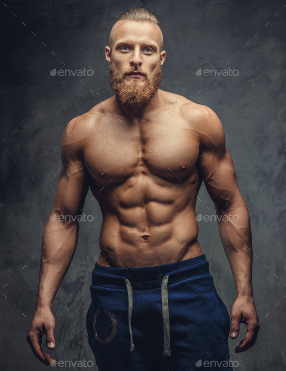 Bodybuilder with beard posing over grey background. Stock Photo by fxquadro
