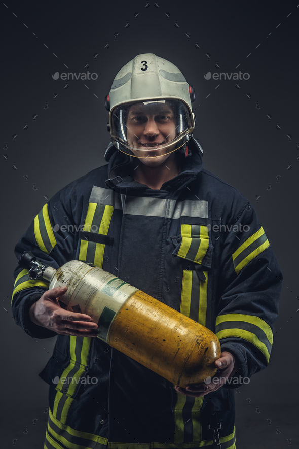 Firefighter rescue holds yellow oxygen tank. Stock Photo by fxquadro