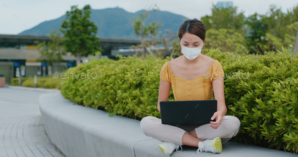 Women wear a face mask and use of laptop computer at park Stock Photo ...