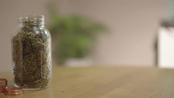 Pan to reveal marijuana in a jar, a grinder, and a vaporizer on a table ...