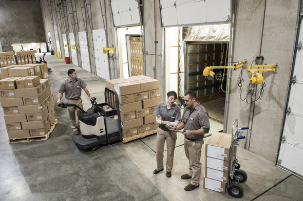 Uniformed warehouse workers loading boxed products into truck in a ...