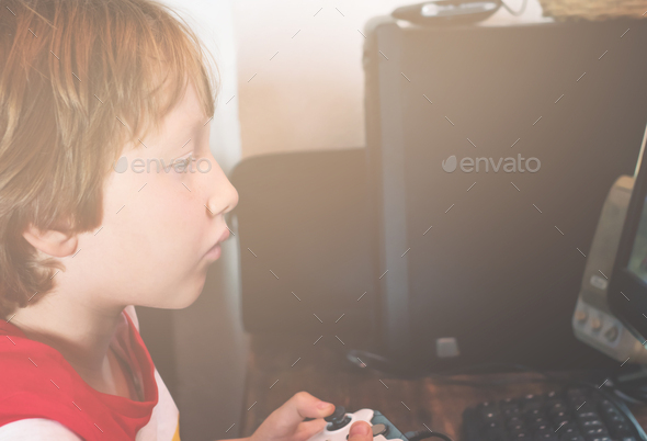 Little kid playing with joystick in front of PC Stock Photo by tenkende
