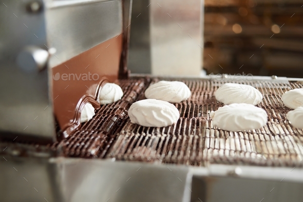 Confectionary conveyor line is covering marshmallow with liquid ...