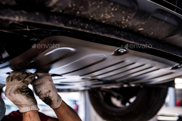 Mechanic installs underbody protection on a raised car Stock Photo by ...