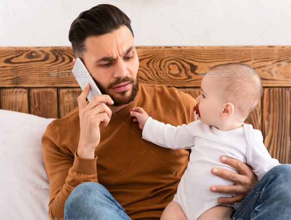 Father Talking On Phone Sitting With Baby Toddler In Bedroom Stock ...
