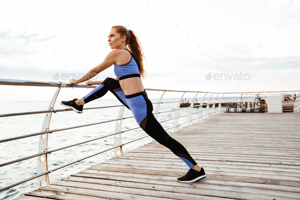 Image of redhead athletic sportswoman doing exercise while working out ...