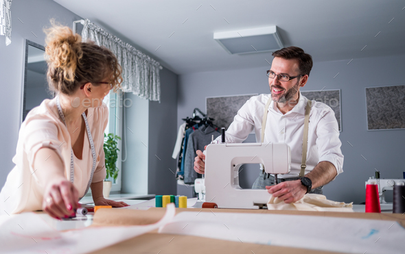 Professional tailors during work on project using sewing machine at ...