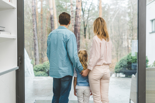back view of family looking out window at home Stock Photo by ...