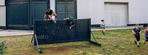 Participants in obstacle course running and climbing wall Stock Photo ...