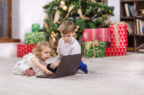 Young girl and boy watching video on laptop computer beside Christmas ...
