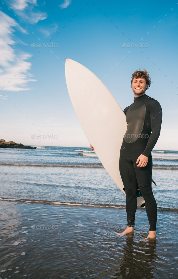 Surfer standing in the ocean with his surfboard. Stock Photo by megostudio