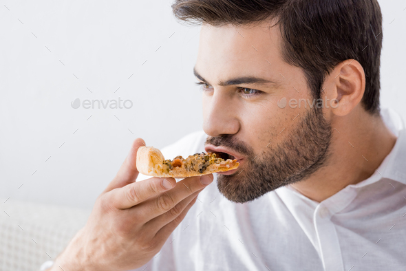 portrait of young man eating pizza alone at home Stock Photo by ...
