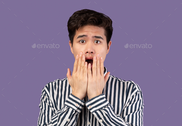 Scared asian man grimacing, shocked at purple studio Stock Photo by ...