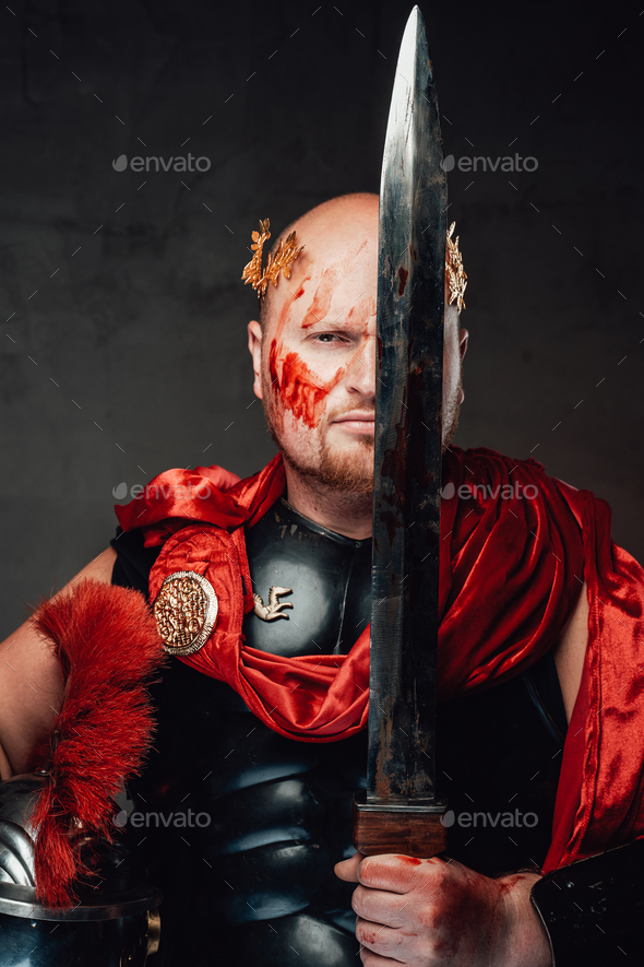 Roman guardian poses with sword near his face in dark background Stock ...