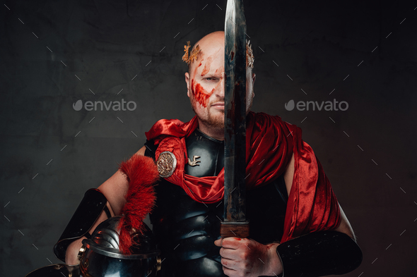 Roman guardian poses with sword near his face in dark background Stock ...