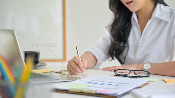 Working women taking notes in the office. Stock Photo by poungsaed_eco