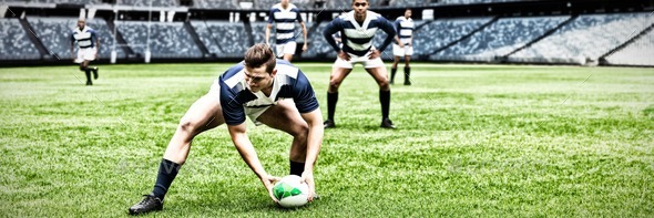 Digital composite image of rugby player picking up the ball in sports ...