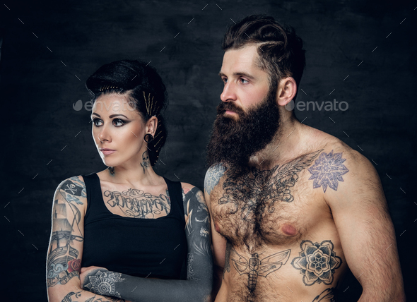 Studio portrait of full body tattooed couple over dark grey background ...
