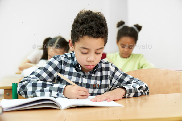 Front view of little boy in process of doing test at school Stock Photo ...
