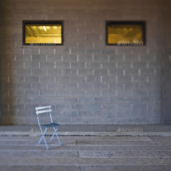 Folding chair in front of concrete block wall. Stock Photo by Mint_Images