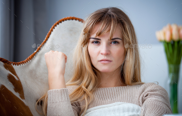 Angry woman sitting on armchair at home looking at camera, negative ...