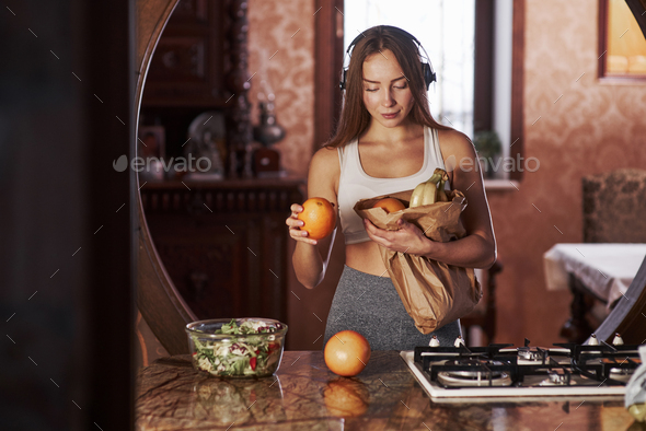 From the mall. Young woman standing in the modern kitchen near gas ...