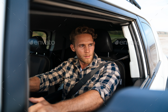 Handsome young man on a front seat of car Stock Photo by vadymvdrobot