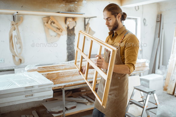 Carpenter with window frame at the workshop Stock Photo by RossHelen
