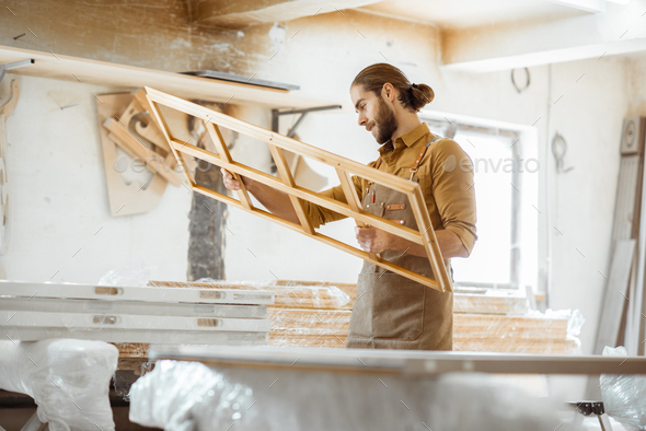 Carpenter with window frame at the workshop Stock Photo by RossHelen