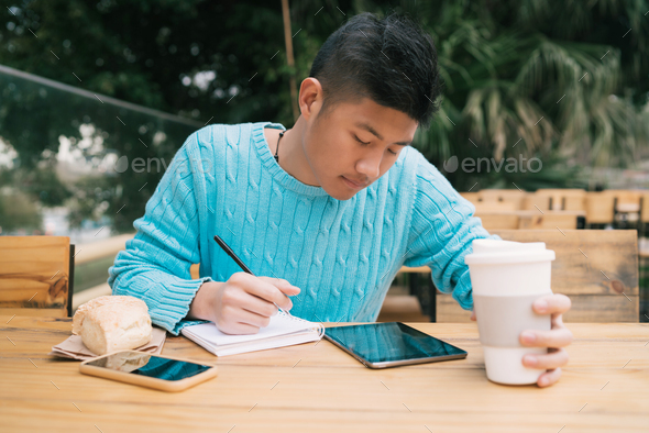Asian man studying in coffee shop. Stock Photo by megostudio | PhotoDune