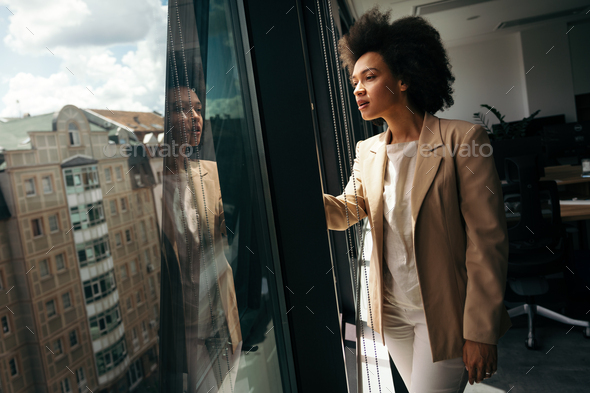 Beautiful african business woman looking outside window in office Stock ...