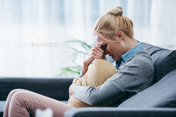 sad woman sitting on couch, crying and holding pillow at home Stock ...