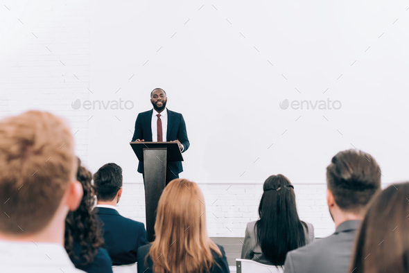smiling african american lecturer talking to audience during seminar in ...