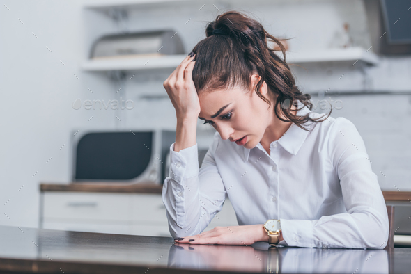 upset woman in white blouse sitting at table and crying in kitchen ...
