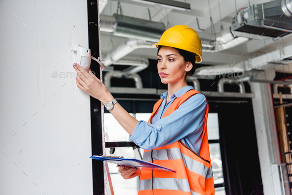 beautiful firefighter checking fire alarm while holding clipboard Stock ...