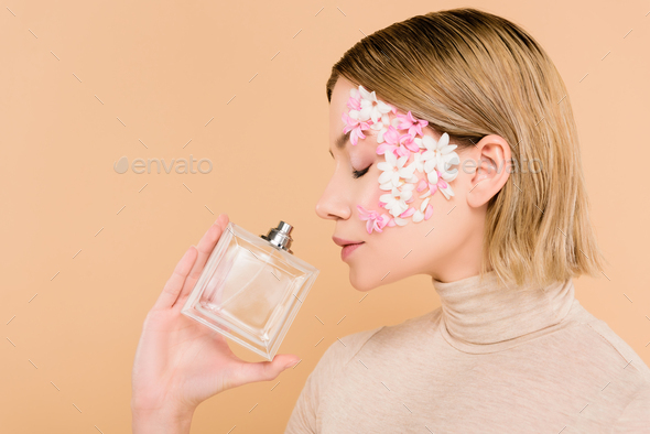 beautiful woman with flowers on face smelling perfume isolated on beige ...