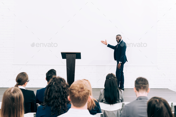 smiling african american lecturer talking to audience during seminar in ...