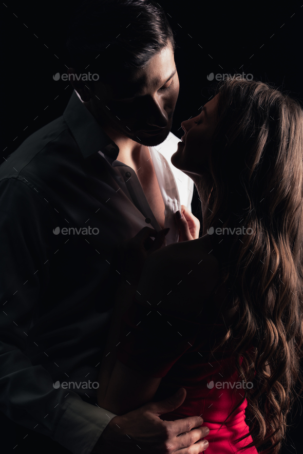 romantic couple embracing and touching each other isolated on black ...