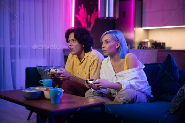 Happy boyfriend and girlfriend playing video games and holding ...
