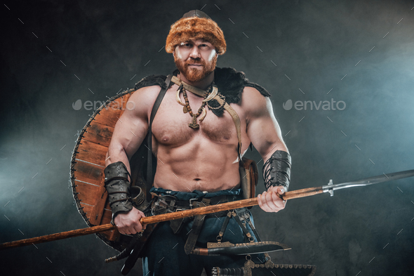 Shirtless viking armed with spear poses in smokey background Stock ...
