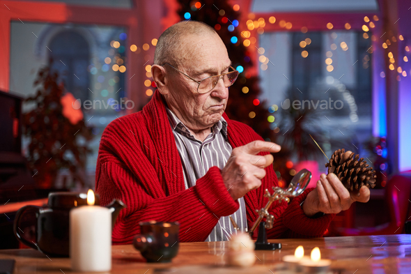 Concentrated and serious old man making decoration at table Stock Photo ...