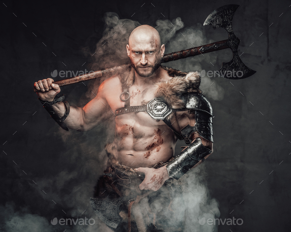 Holding axe on his shoulder savage nordic warrior in smokey background ...