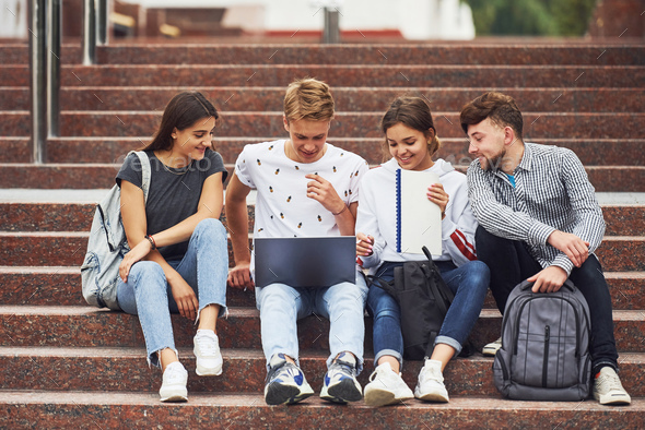 With laptop. Group of young students in casual clothes near university ...
