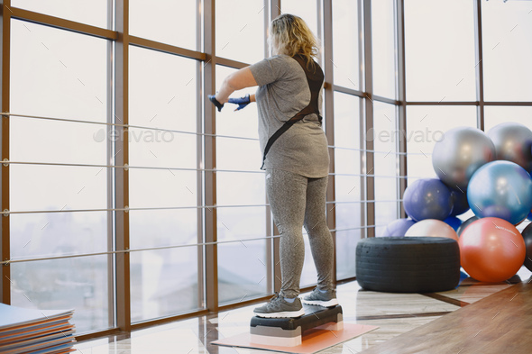 Adult fat woman doing gymnastics at the gym Stock Photo by prostooleh