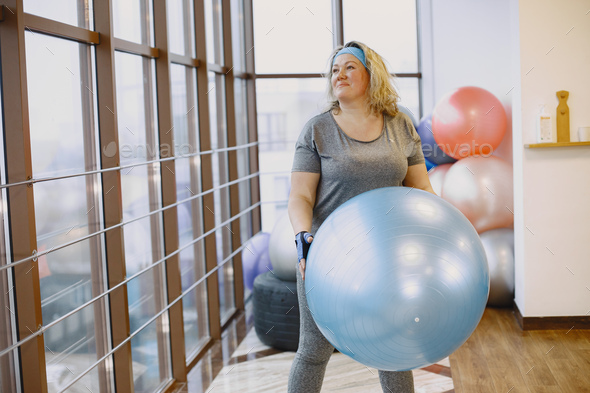 Adult fat woman doing gymnastics at the gym Stock Photo by prostooleh