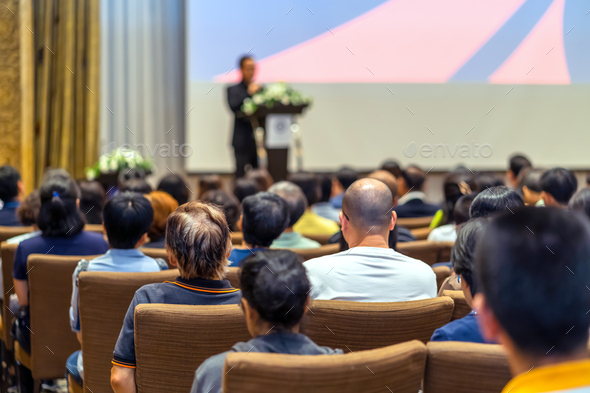 Back side of audience listening the Speaker with podium on the stage in ...