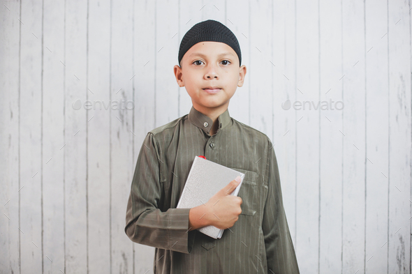 Muslim boy holding Holy Quran and smiling Stock Photo by Garakta-Studio